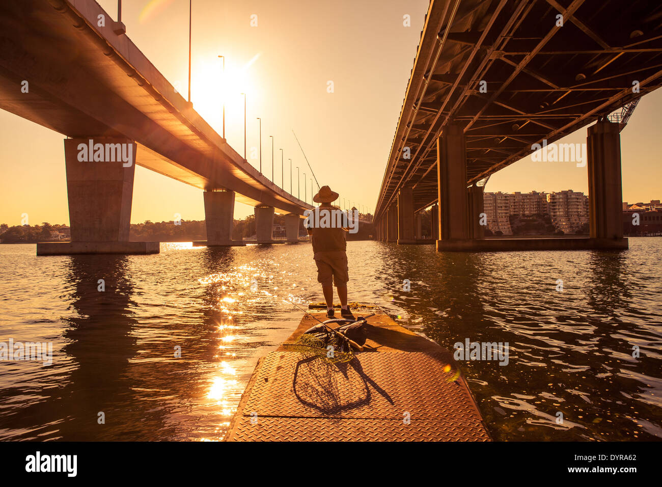 A man fishing next to two bridges in inner Sydney, Australia Stock ...