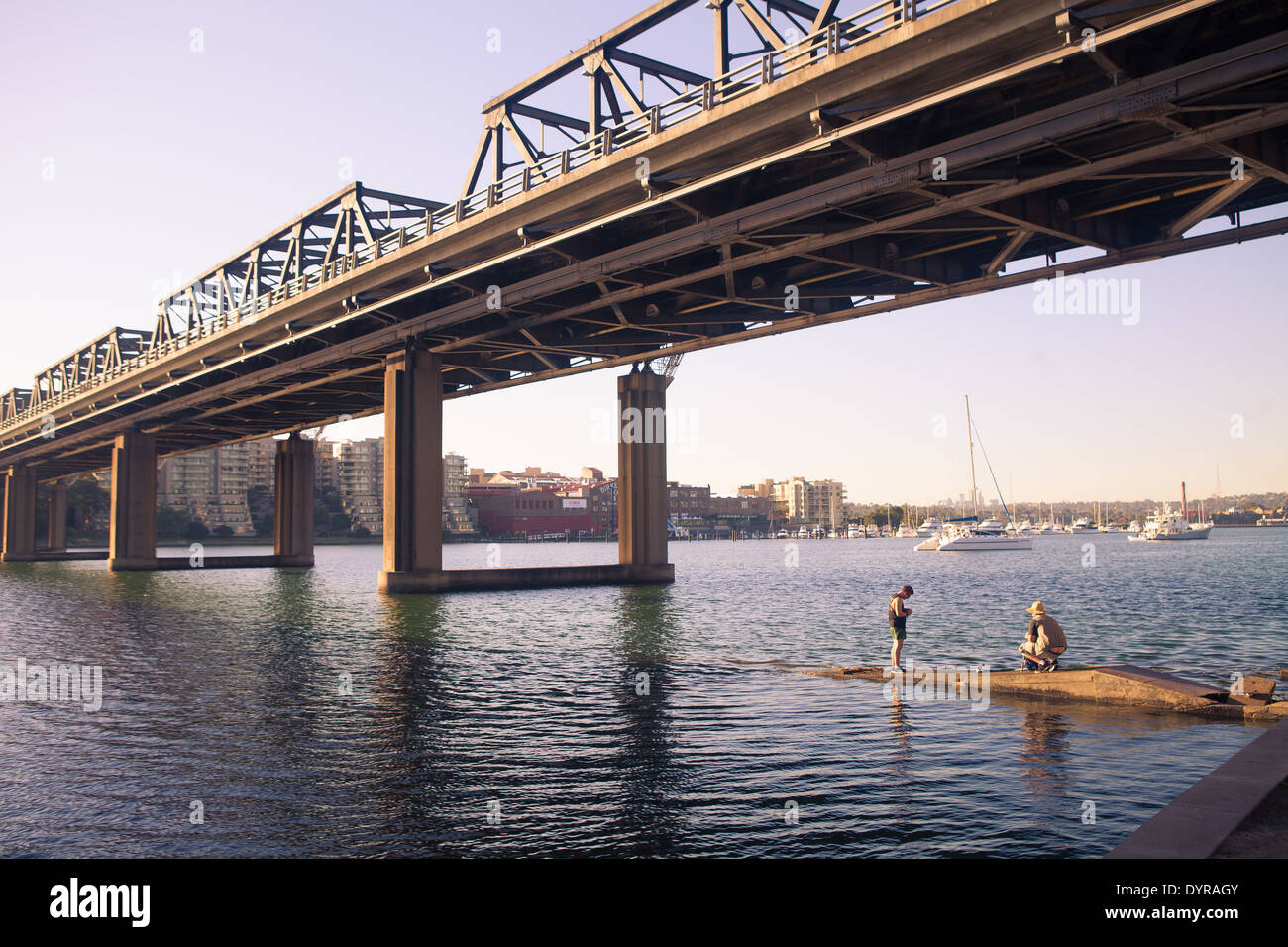 Two men fishing under an old iron road bridge in Sydney Harbour Stock ...