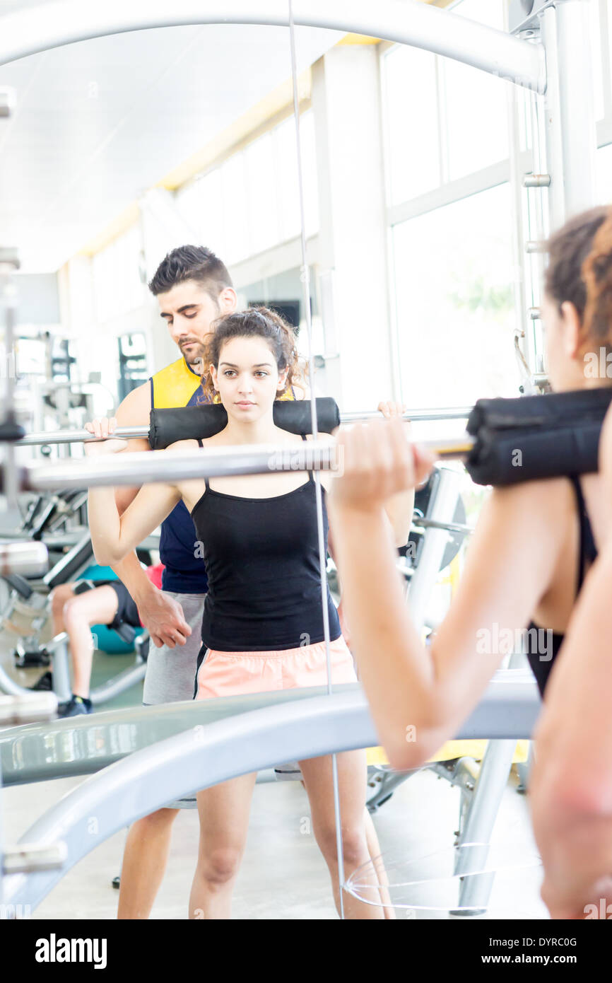 Beautiful young woman working out at the gym with the help of her ...