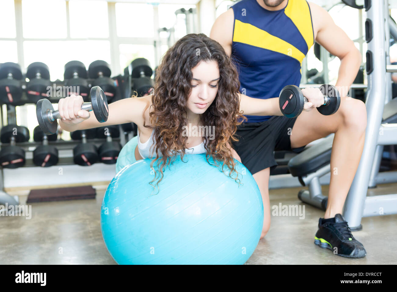 Beautiful young woman working out at the gym with the help of her ...