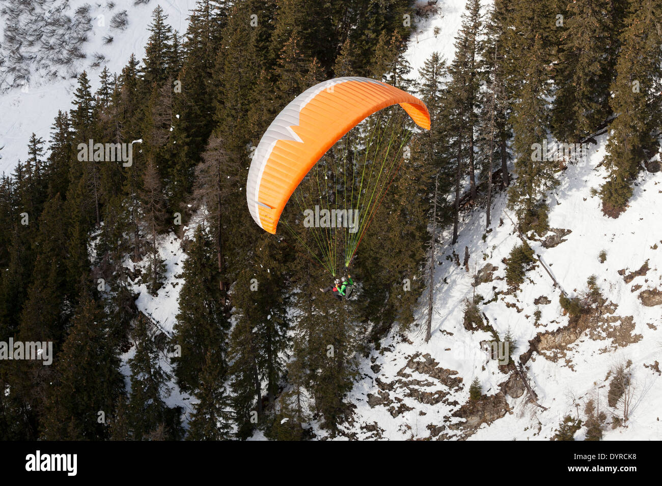 A tourist, tandem paraglides with a guide above the valley of Chamonix ...
