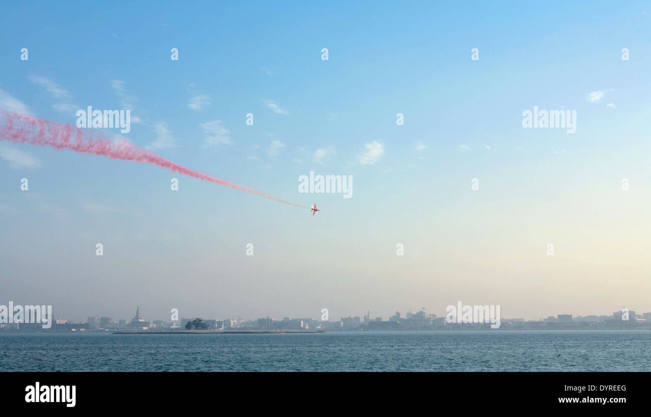 A Red Arrows plane makes smoke as it flies over Doha Bay, Qatar, with ...