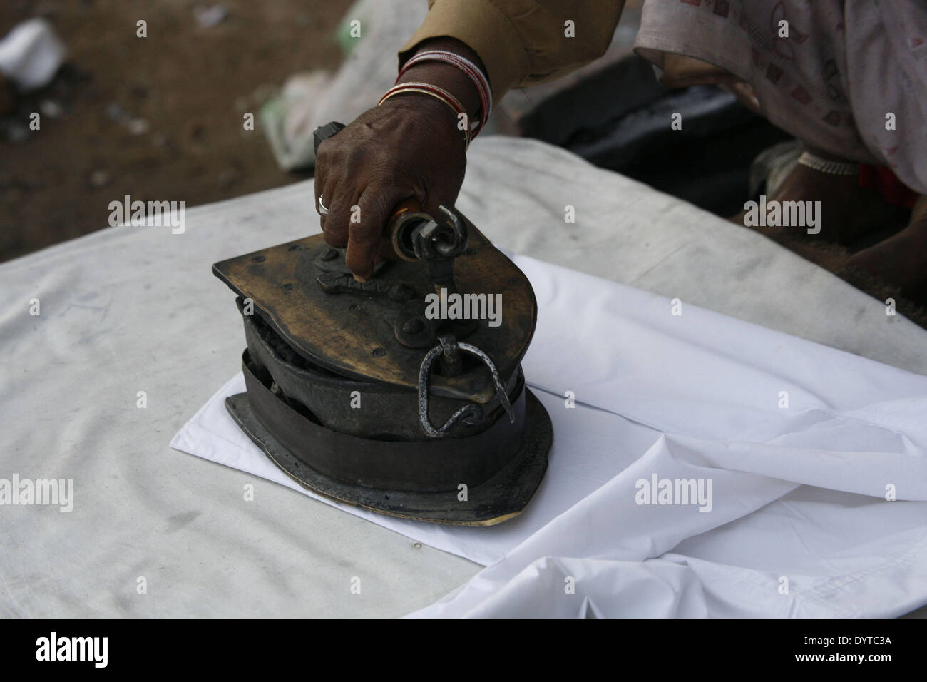 A worker iron a shirt with a coal filled iron at Agra Stock Photo - Alamy