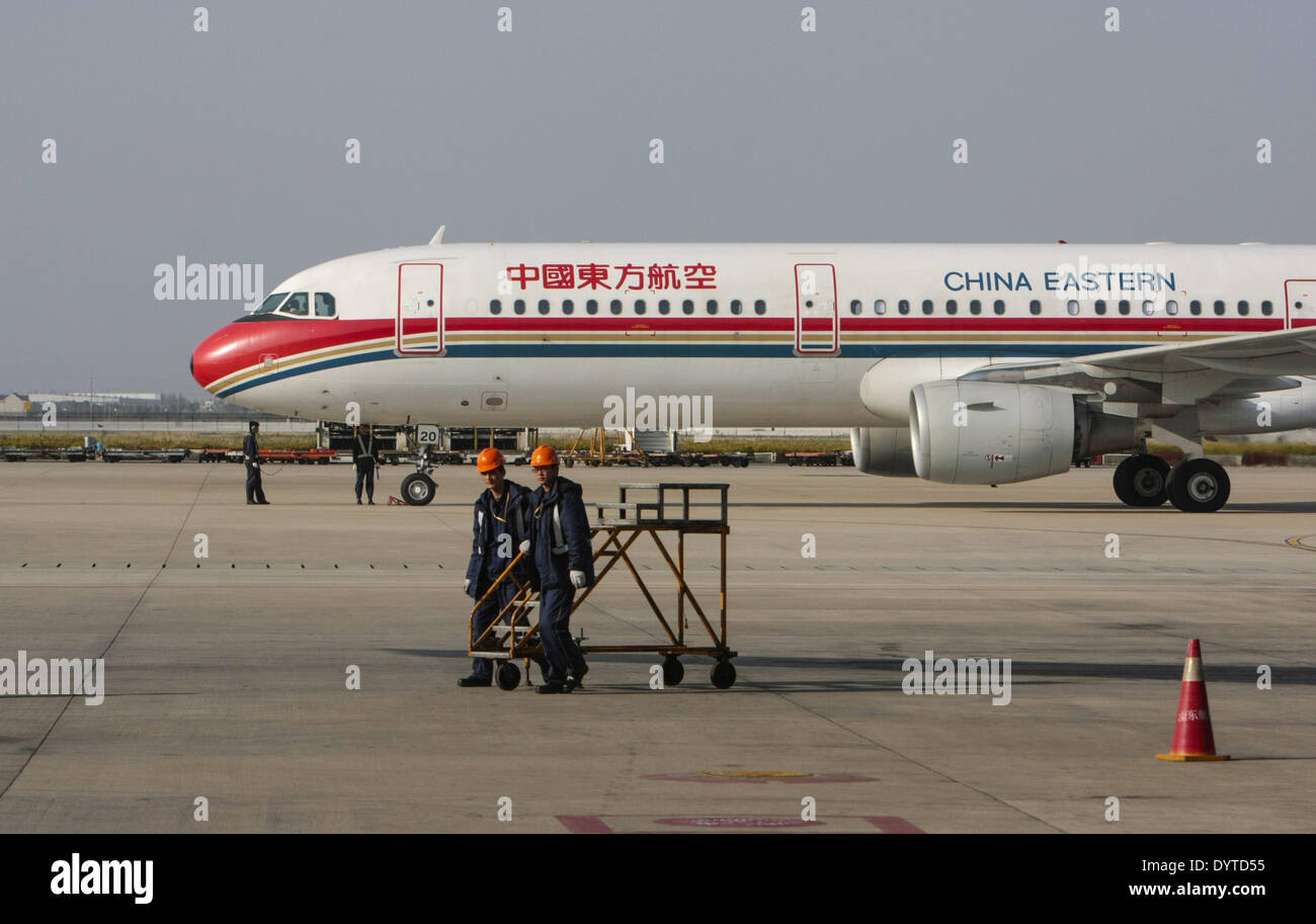 Airport staff walk pass a plane of China Eastern Airline at Shanghai ...