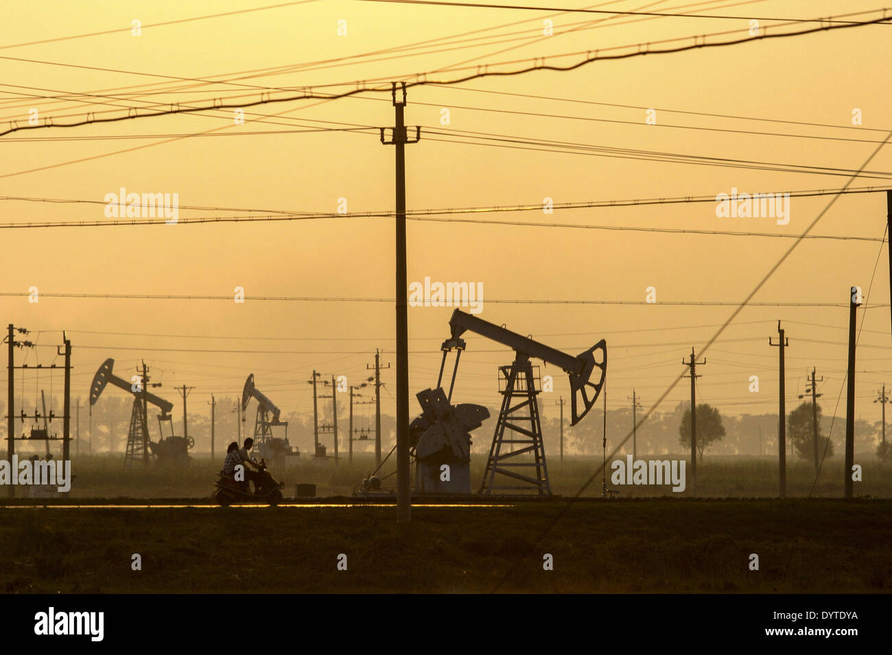 A Chinese couple on motorcycle pass by an oil well at Sinopec's Shengli ...