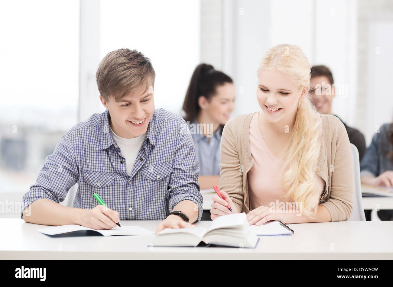 two teenagers with notebooks and book at school Stock Photo - Alamy
