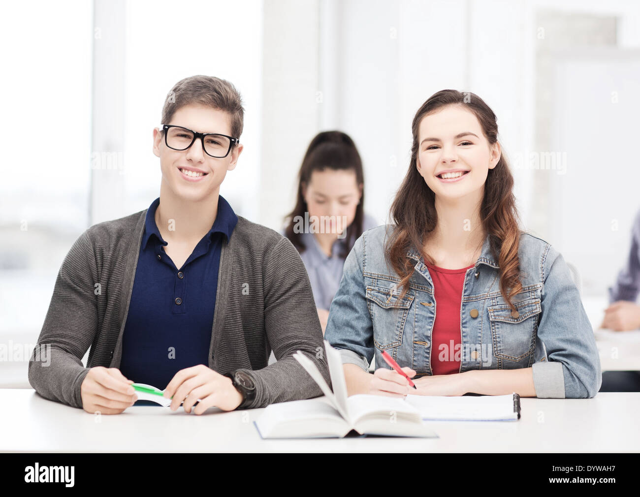 two teenagers with notebooks and book at school Stock Photo - Alamy