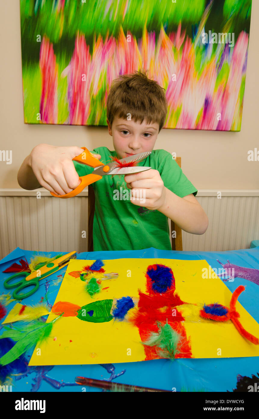 eight year old boy doing arts and craft montage with glue scissors and ...