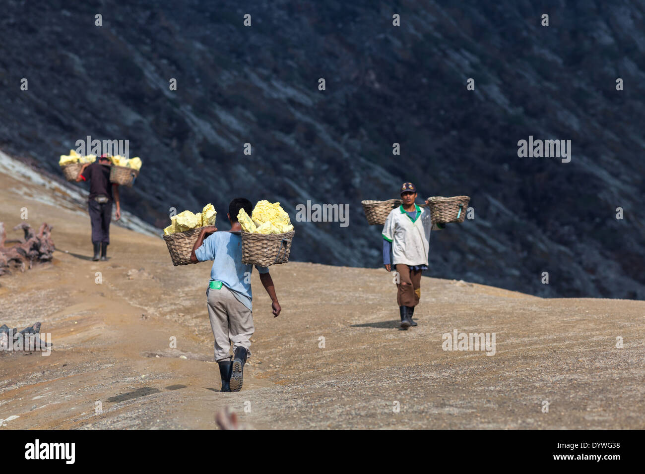 Men carrying baskets laden with blocks of sulfur, rim of Kawah Ijen ...