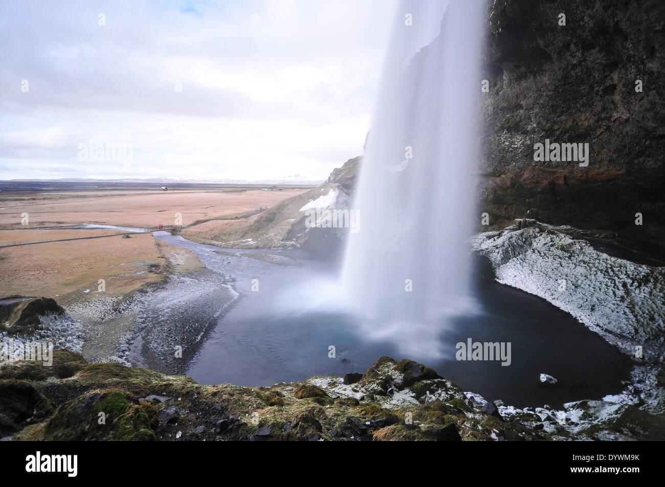 Walking behind the wispy falls of Seljalandsfoss in South Iceland on a ...