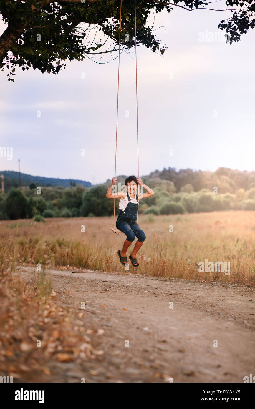 Happy young boy playing on swing in a park Stock Photo - Alamy