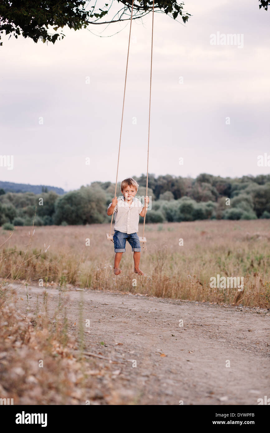 Happy young boy playing on swing in a park Stock Photo - Alamy