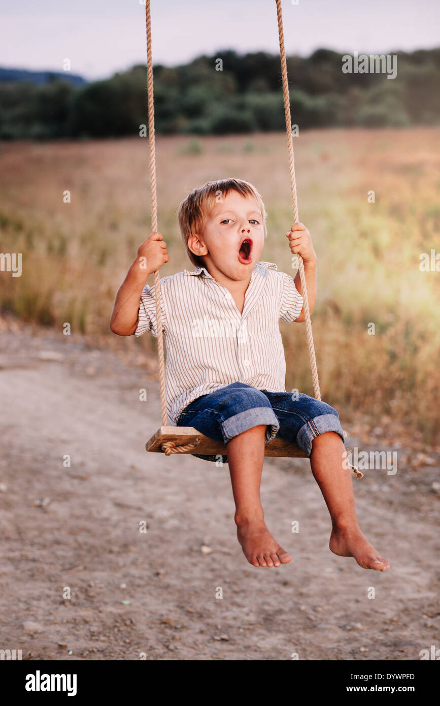 Happy young boy playing on swing in a park Stock Photo - Alamy