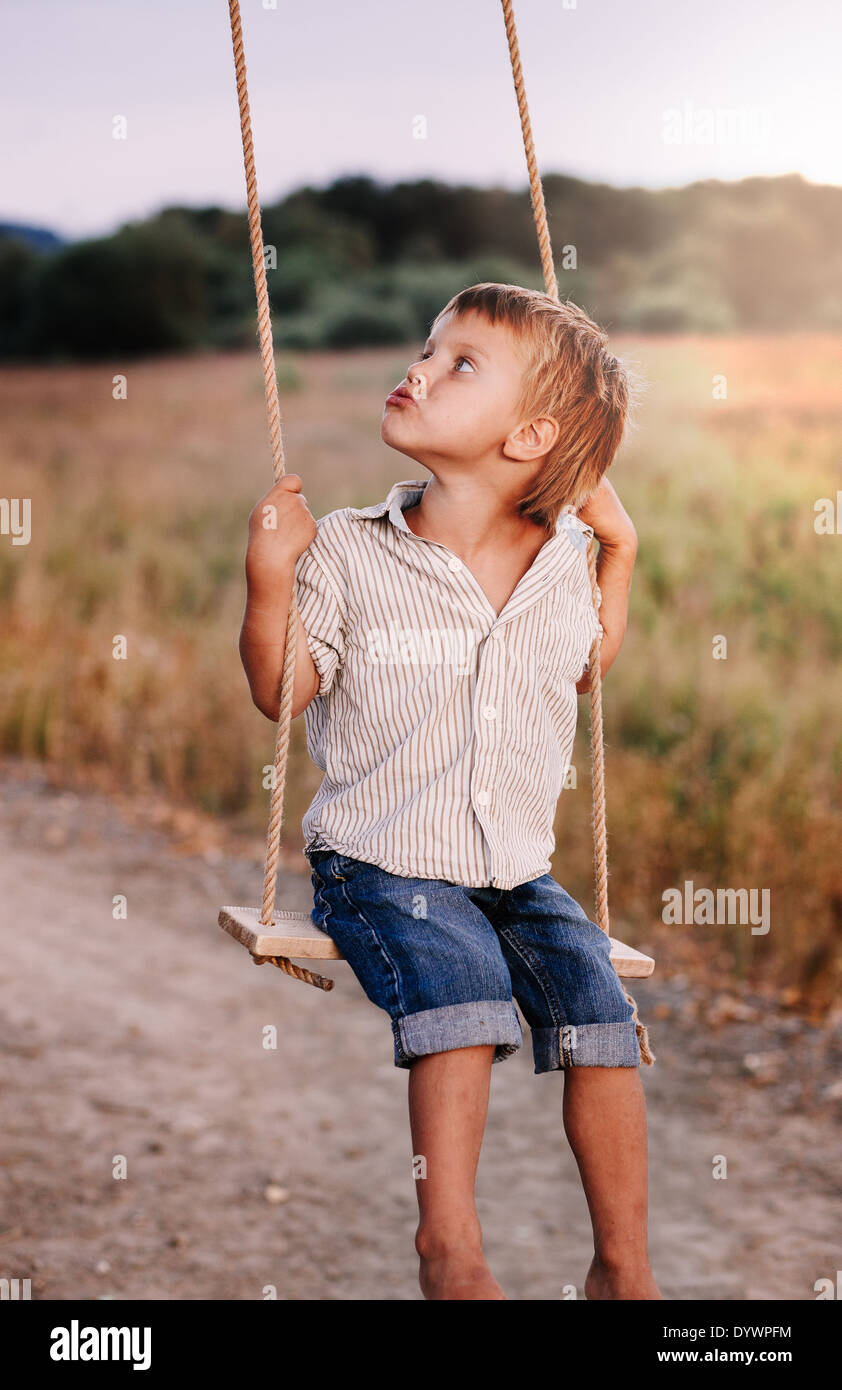 Happy young boy playing on swing in a park Stock Photo - Alamy