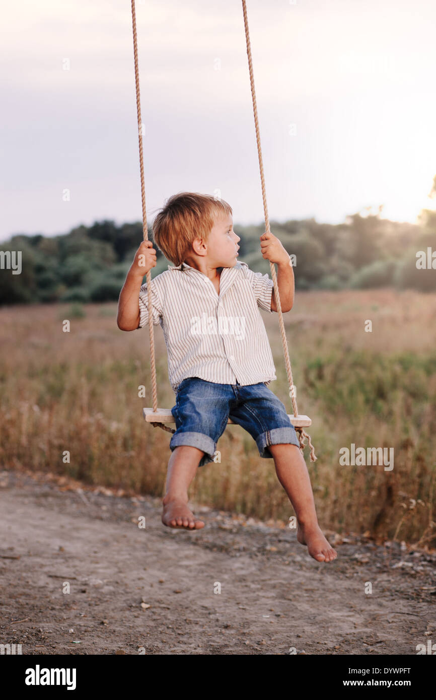 Happy young boy playing on swing in a park Stock Photo - Alamy