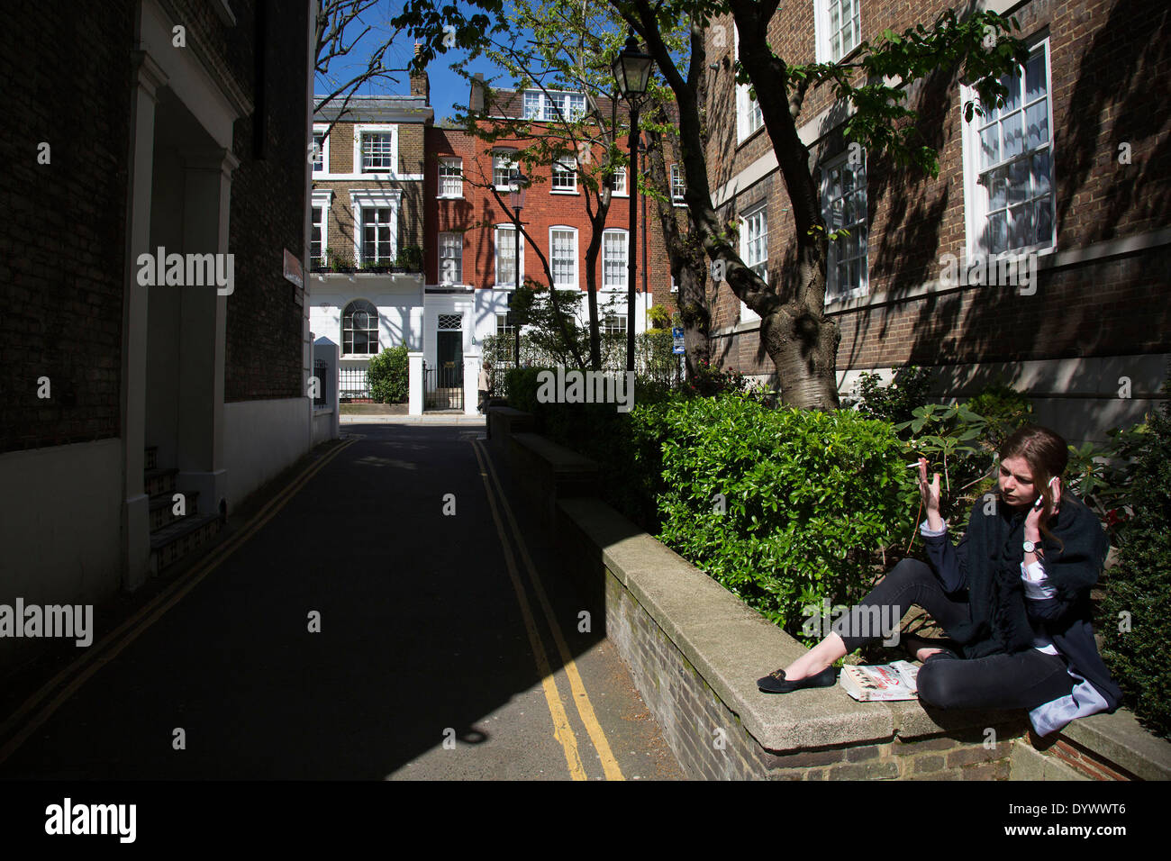 Woman relaxing in the sun talking on her cell phone on Kensington ...