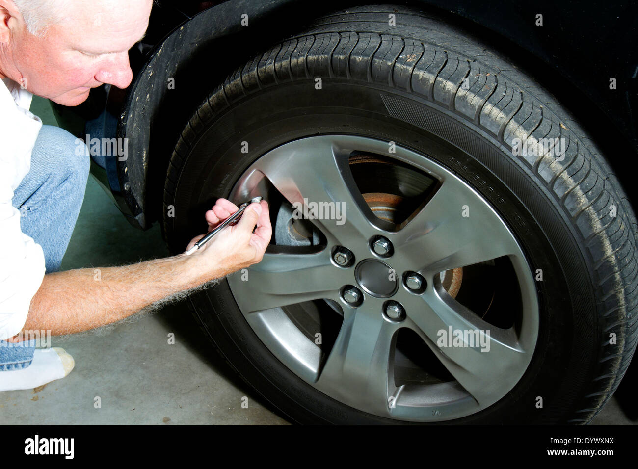 Man checking air pressure on auto tire Stock Photo - Alamy