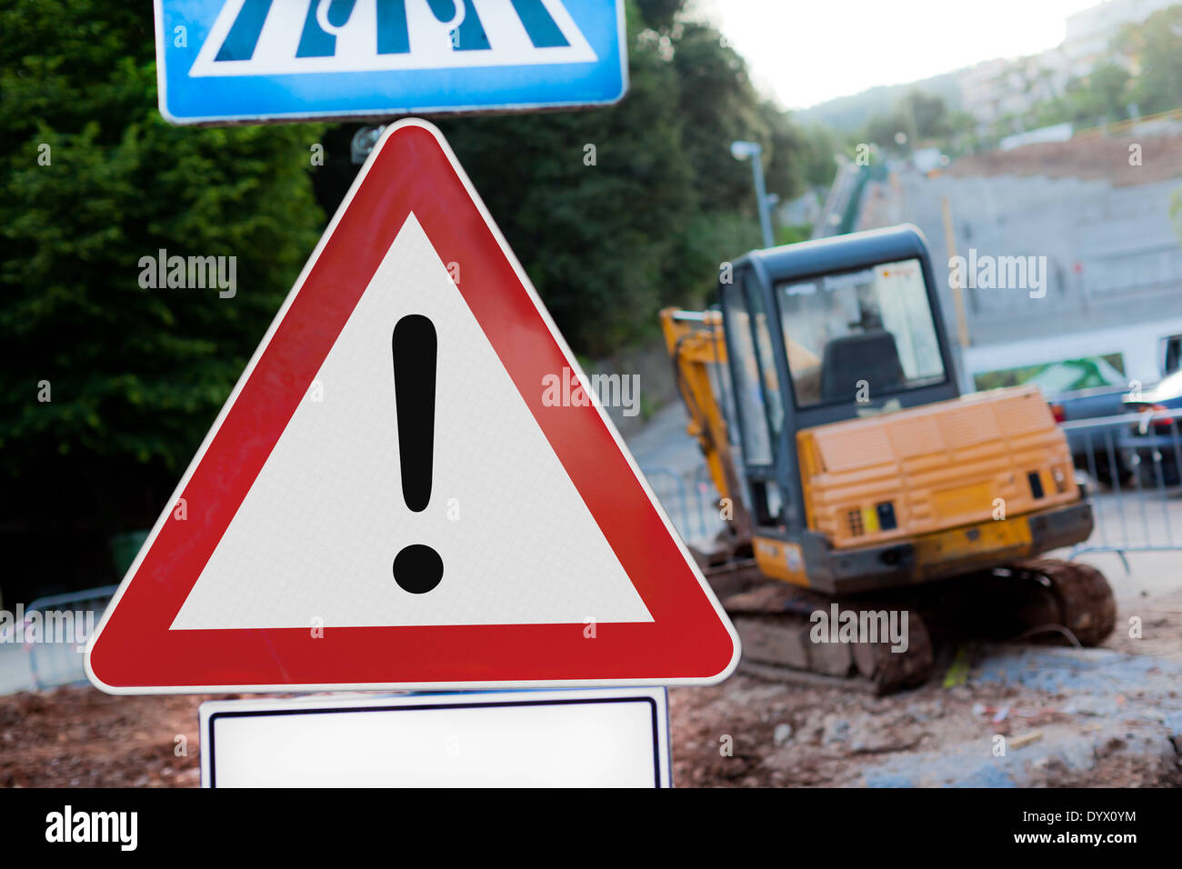 Warning Sign and a blurred excavator in background Stock Photo - Alamy