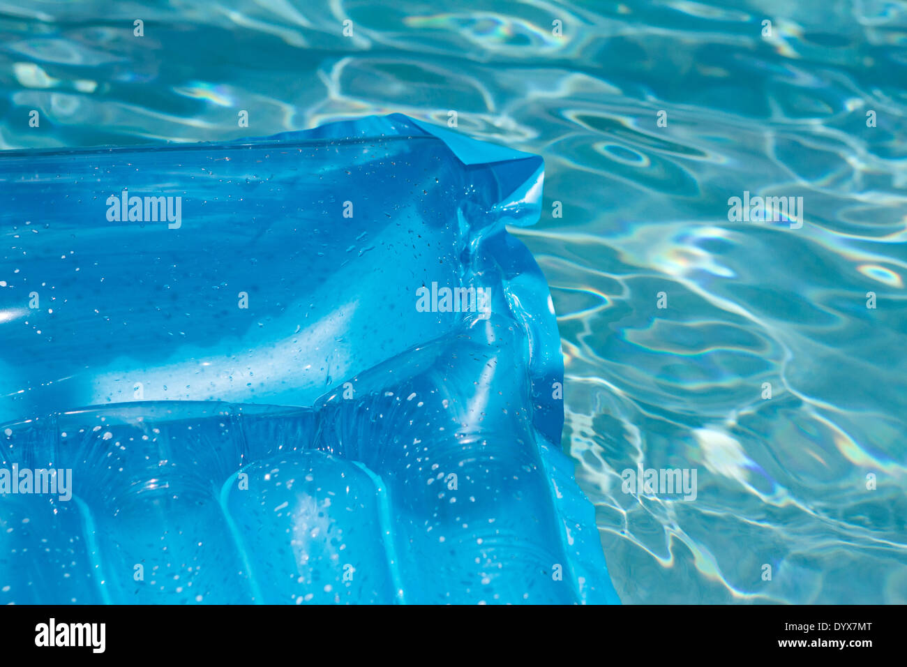 blue water lilo floating on a clear blue swimming pool showing a ...