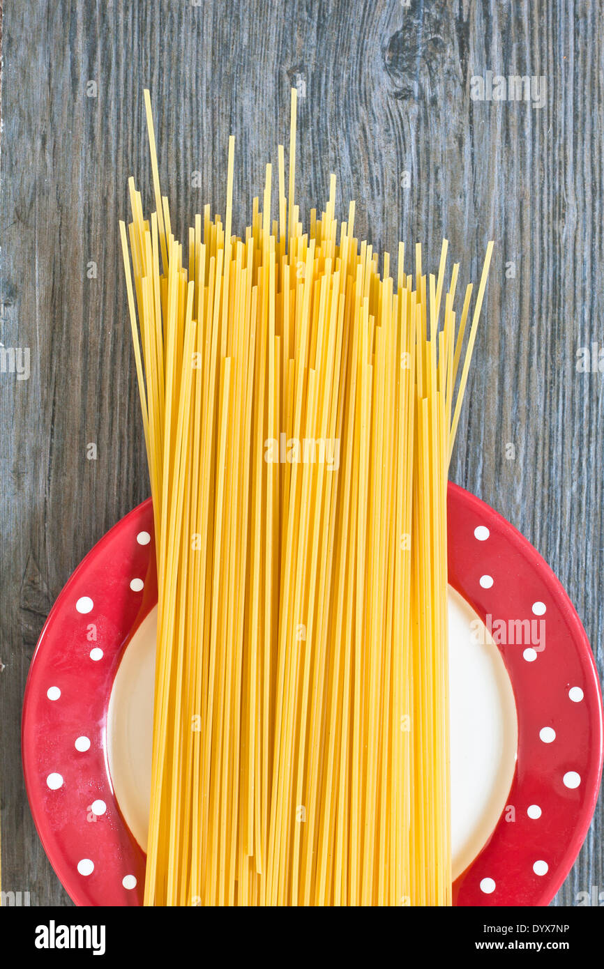 Raw white spaghetti on a red plate Stock Photo - Alamy