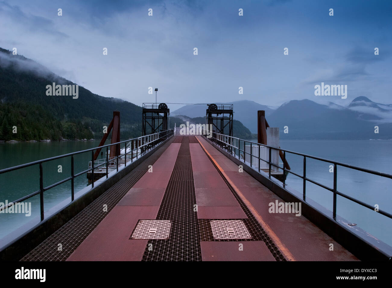 view up industrial pier ramp in calm ocean inlet surrounded by tree ...
