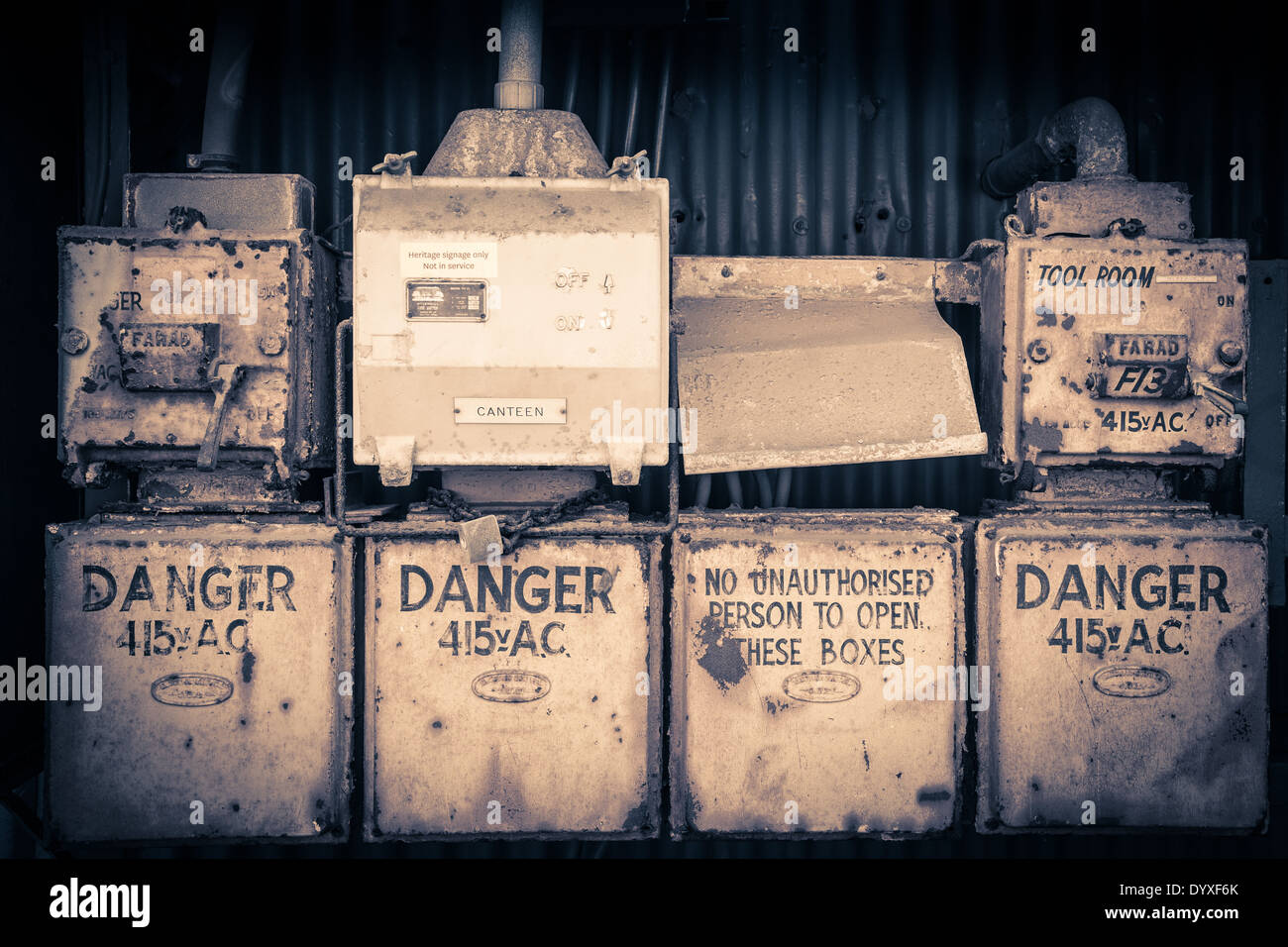 A series of yellow rusty steel power supply boxes outside a factory ...