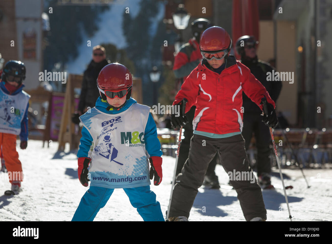 Young children ski through a ski resort after finishing their ski ...