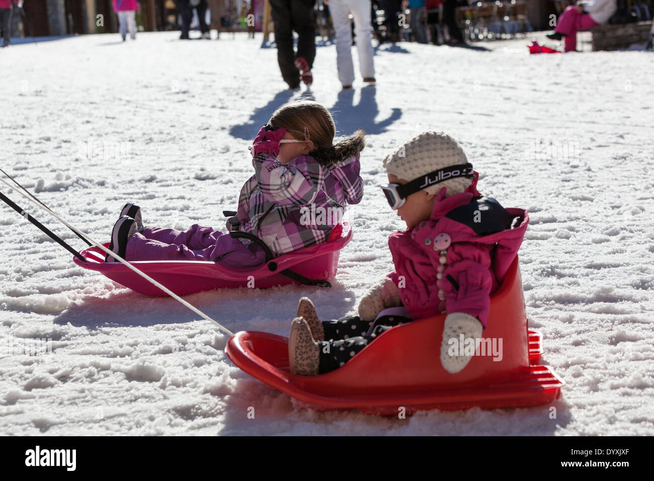 Two young children are pulled along on plastic toboggans in a ski ...