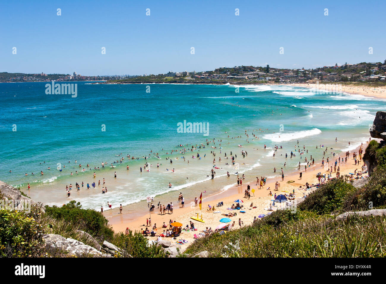 overhead of crowded beach on a summers day with a view down the coast ...