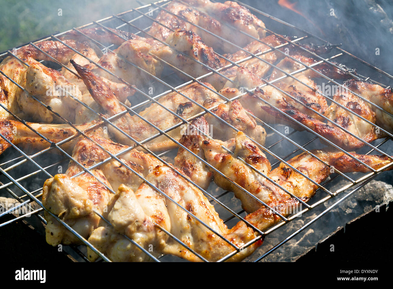 Chicken meat grilled on barbecue in smoke closeup Stock Photo - Alamy