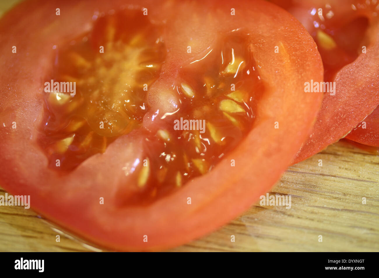 Close up of a slice of red tomato showing the seeds and flesh on a ...