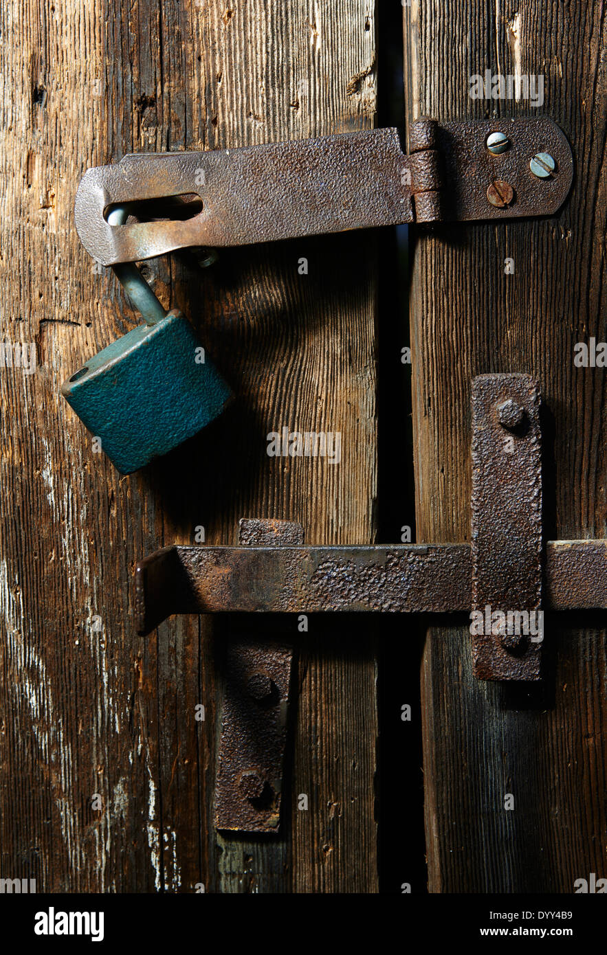 Close up of padlock and old metal hasp and staple on an old wooden door ...