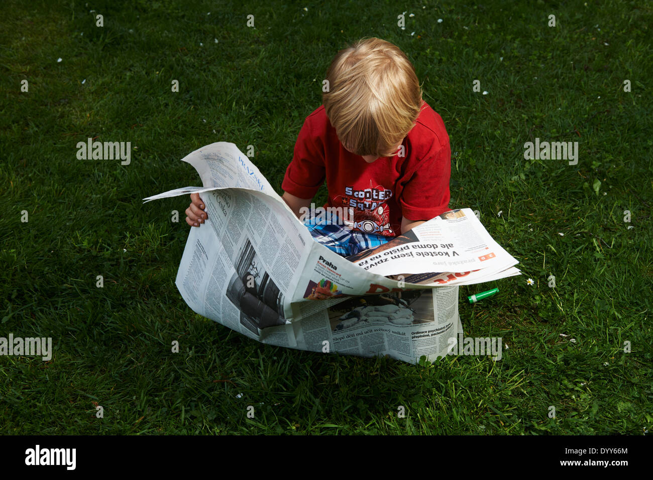 A child blond boy reading newspaper outside at green grass lawn Stock ...