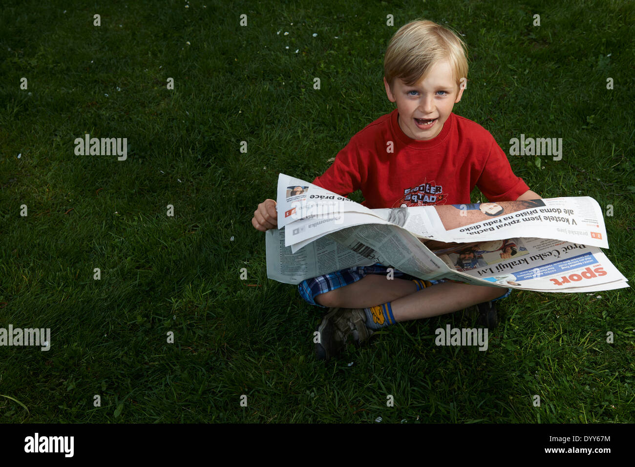 A child blond boy reading newspaper outside at green grass lawn Stock ...