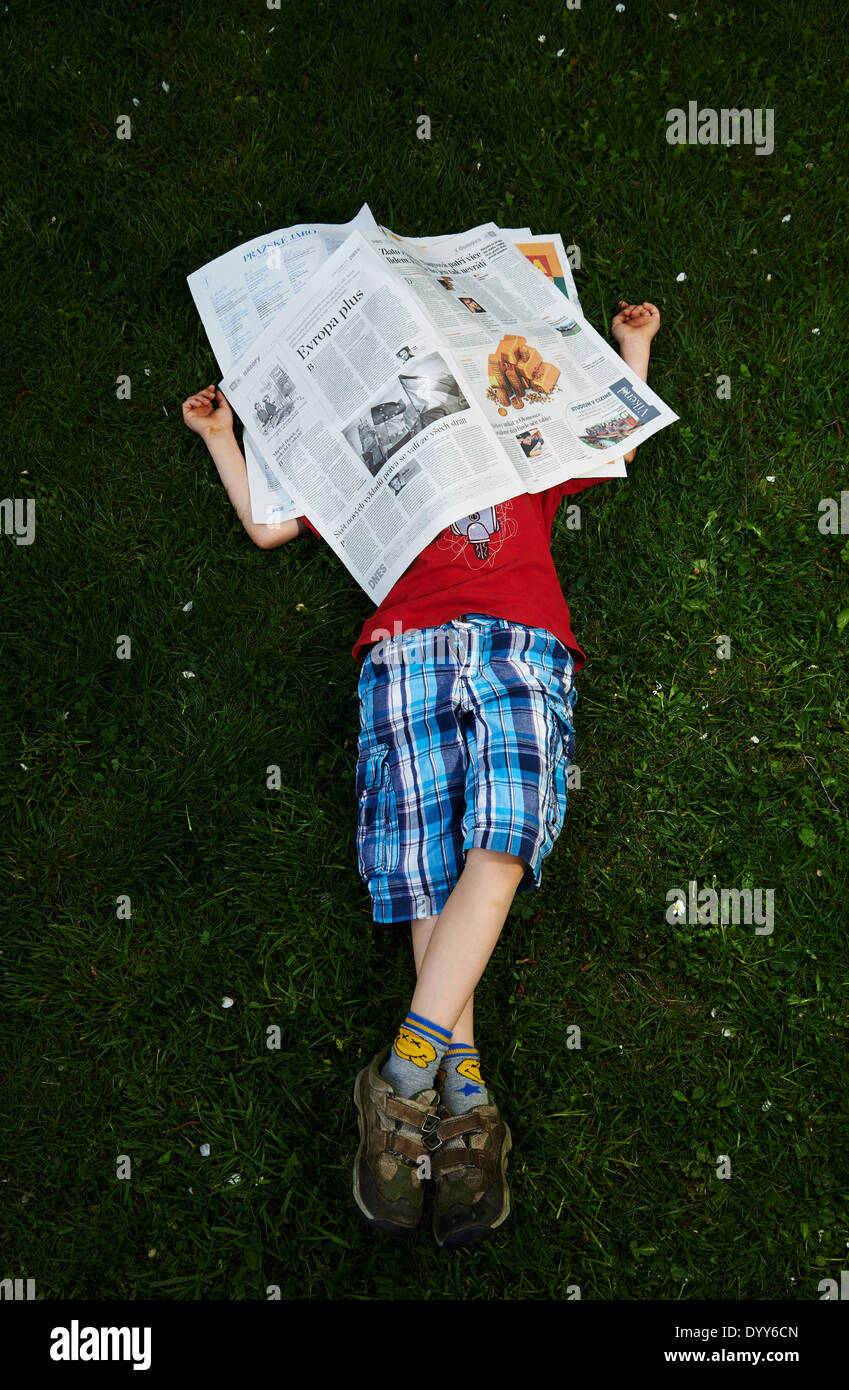 A child blond boy reading newspaper outside at green grass lawn Stock ...