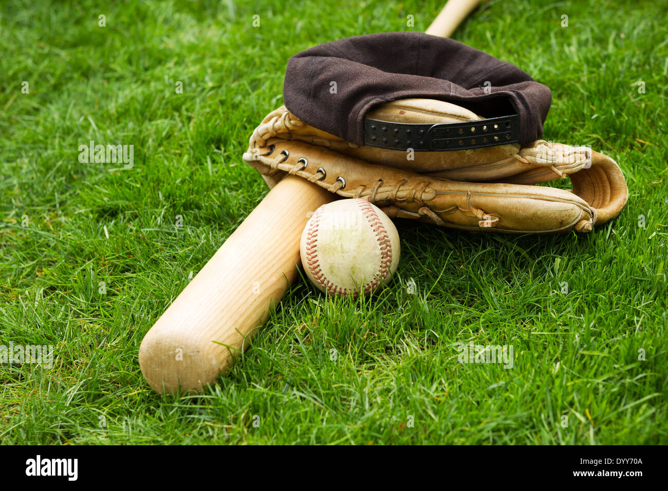 Horizontal photo of old baseball, bat, cap and glove on natural grass ...