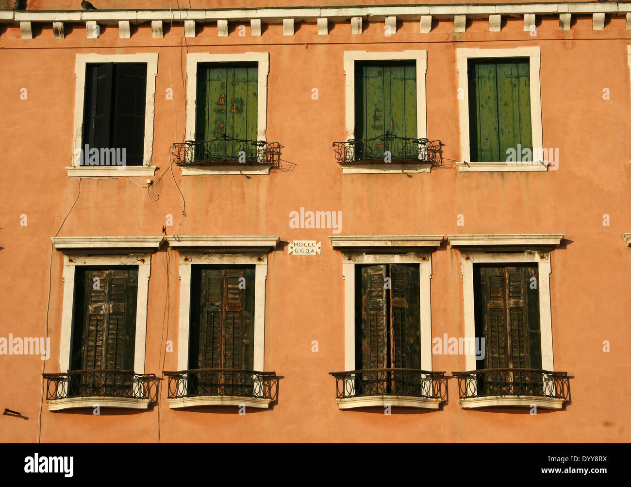 Eight shuttered windows with iron balconies on an orange building in ...