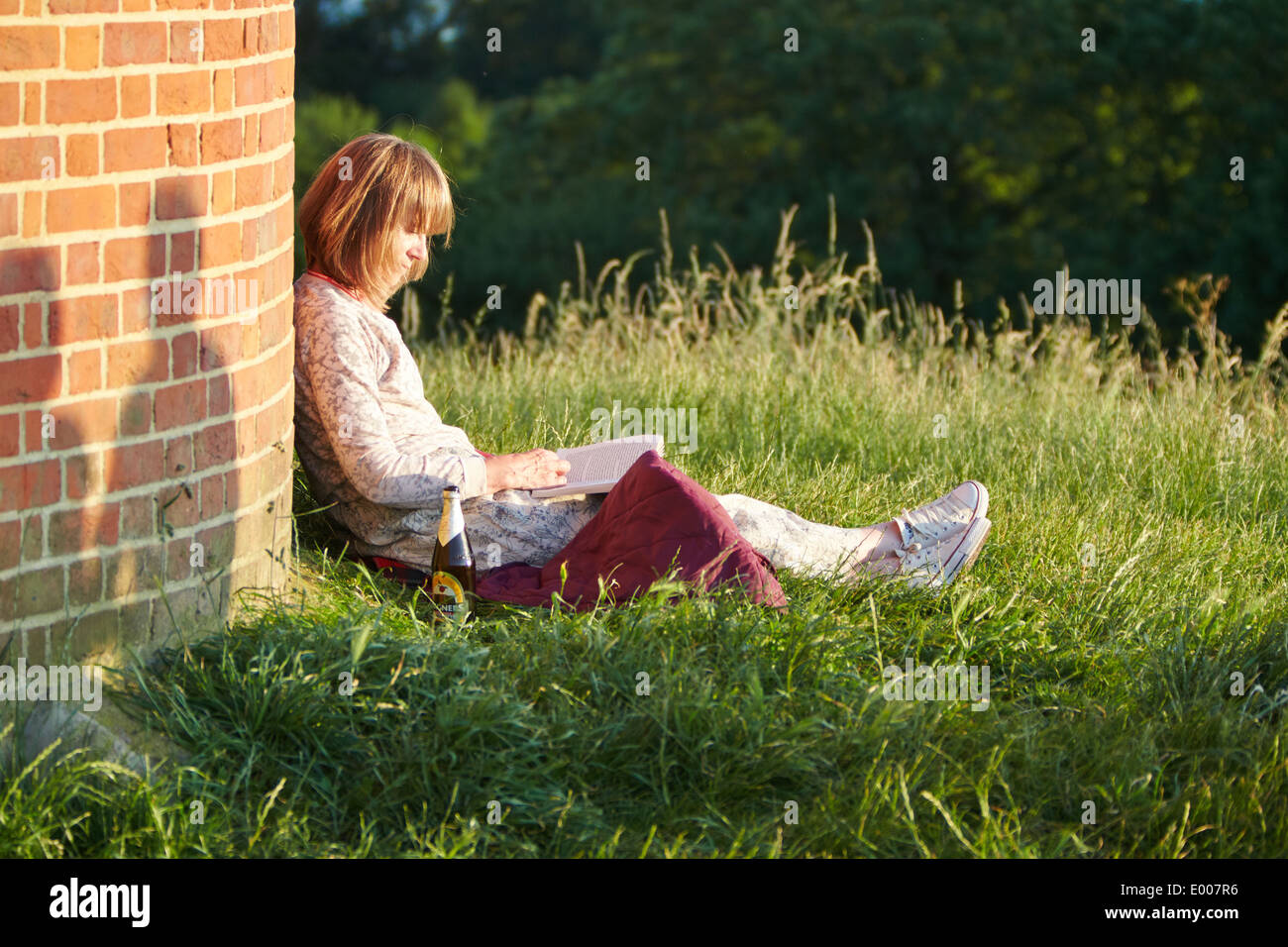 Woman reading book leaning against wall Stock Photo - Alamy