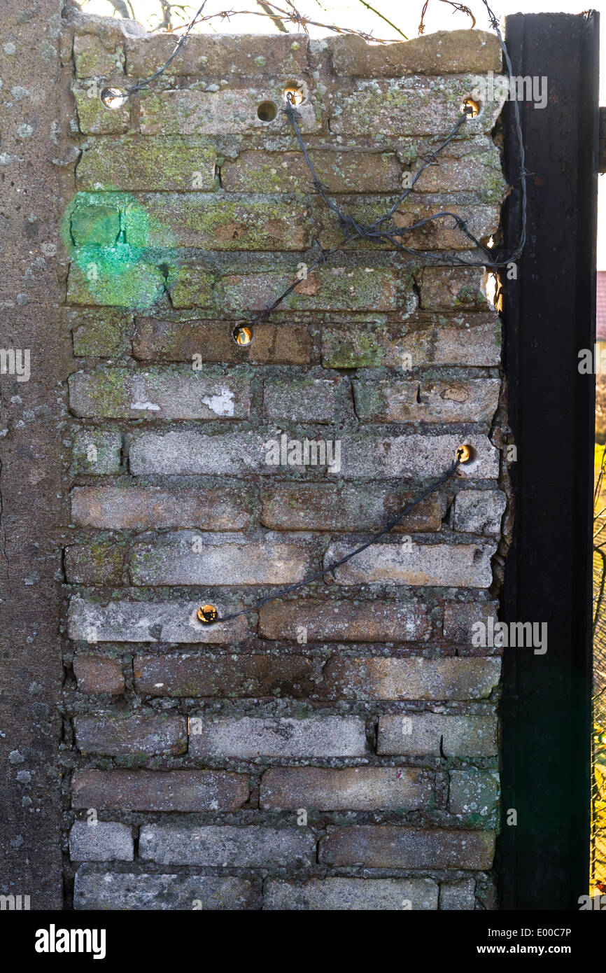 Protective brick wall topped with barbed wire Stock Photo - Alamy