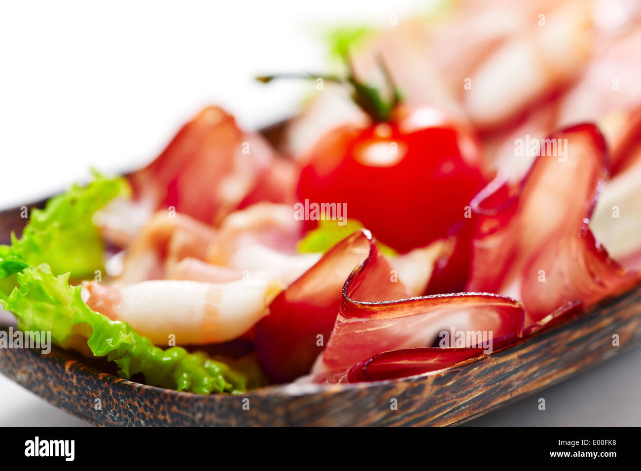 Bacon stripes served with greens and tomato. On white background. Close ...