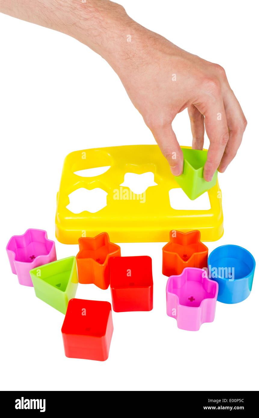 Human hand puts wrong shape into shape sorter toy with various coloured ...