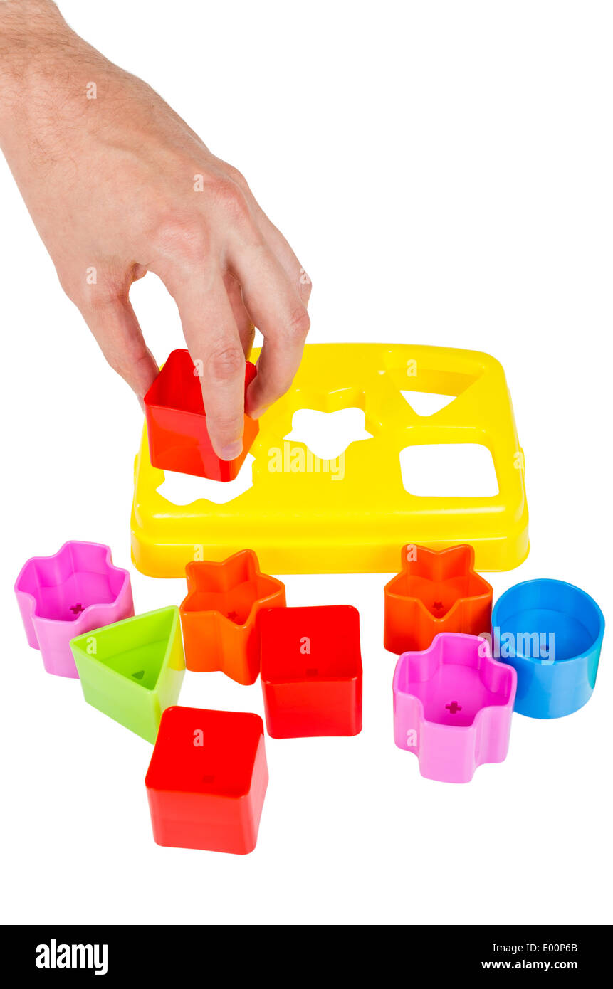Human hand puts wrong shape into shape sorter toy with various coloured ...