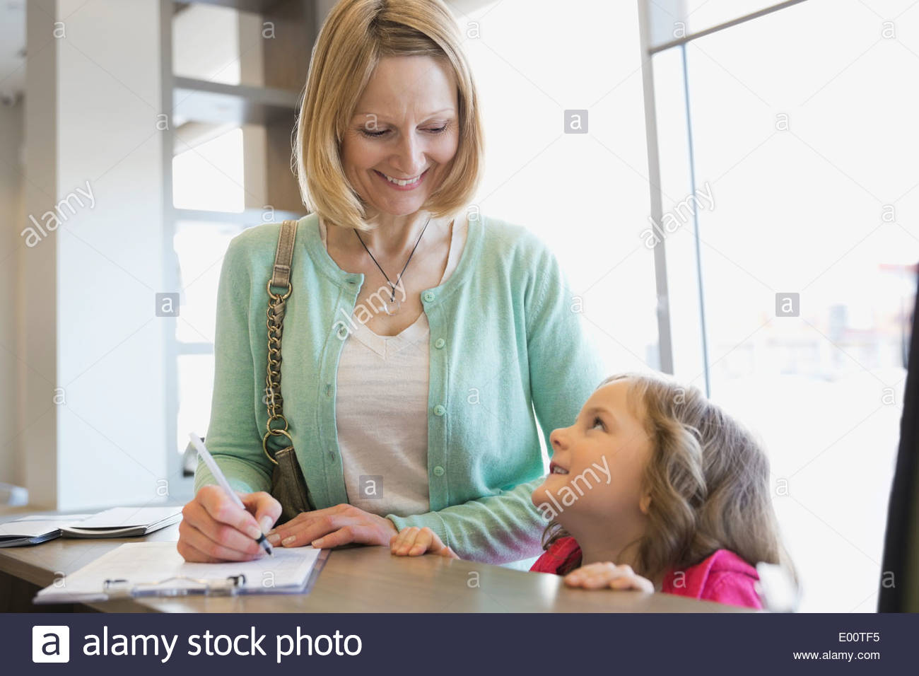 Mother and daughter filling out paperwork at counter Stock Photo - Alamy