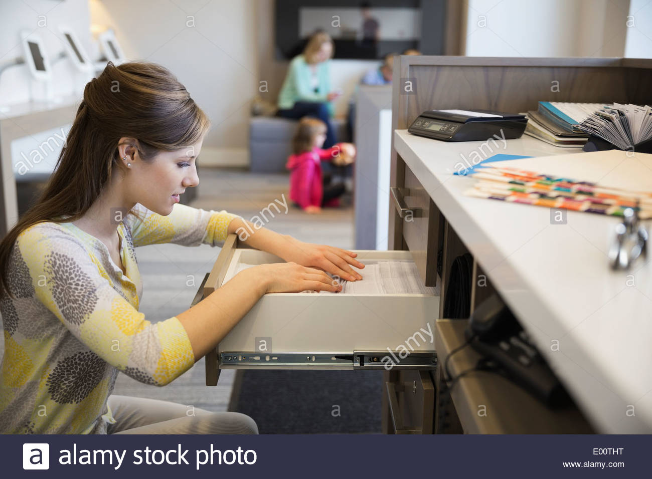 Receptionist looking through drawer in dentists office Stock Photo - Alamy
