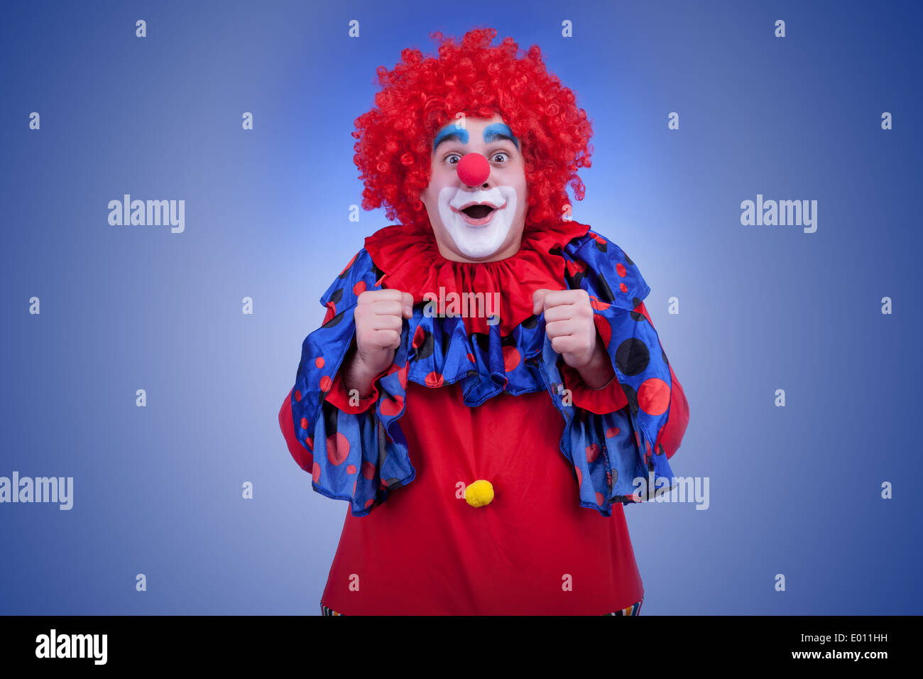 Happy clown in red costume on blue background. Studio professional ...