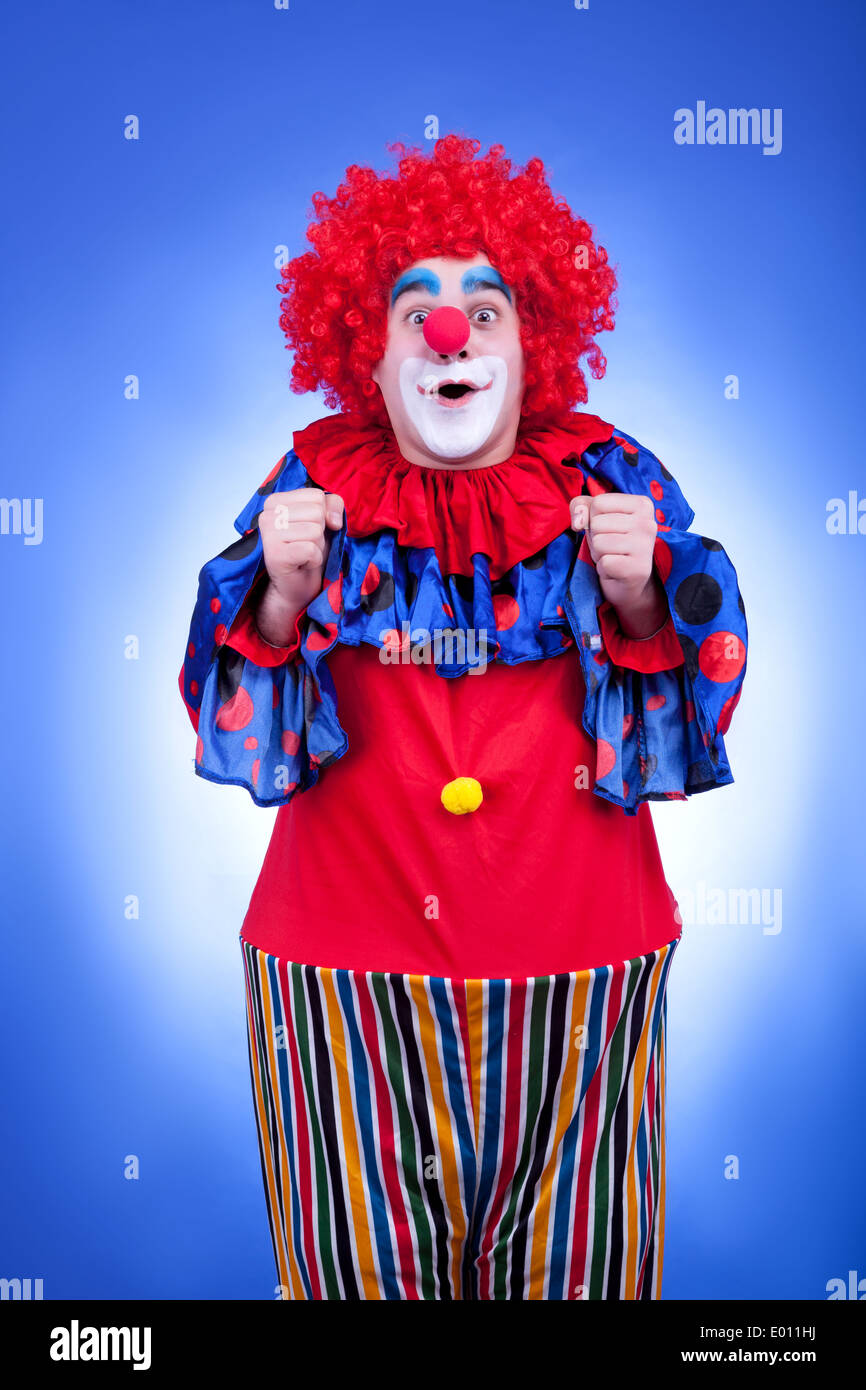 Happy clown in red costume on blue background. Studio professional ...