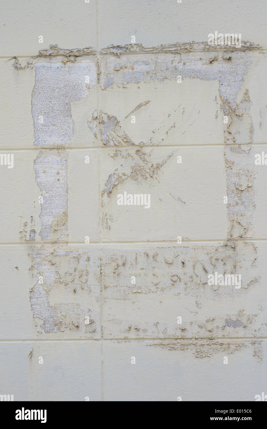 An ivory, vanilla colored grid wall with paper and glue residues. An ...
