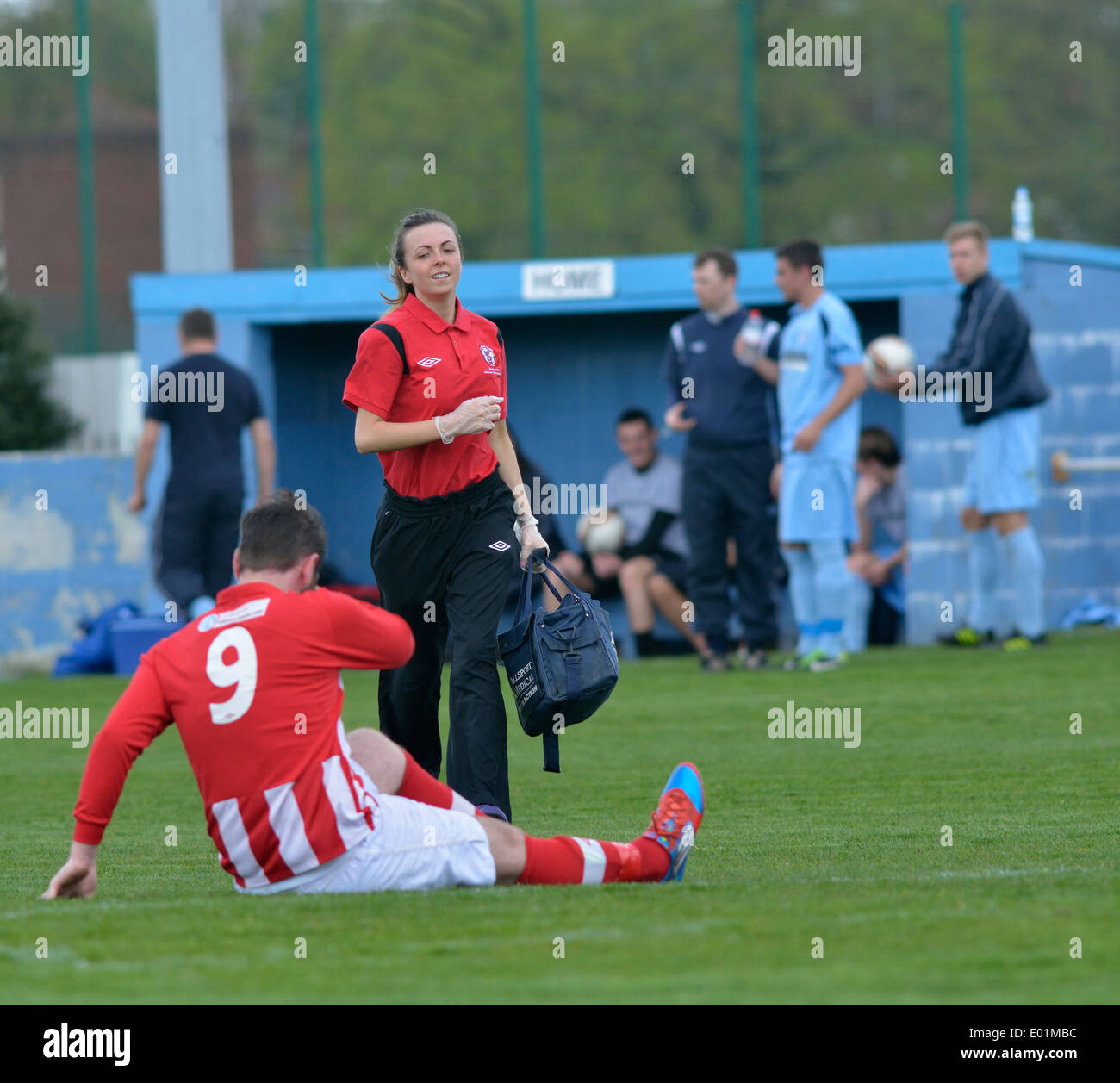 a football player sits injured on the pitch as the physiotherapists ...