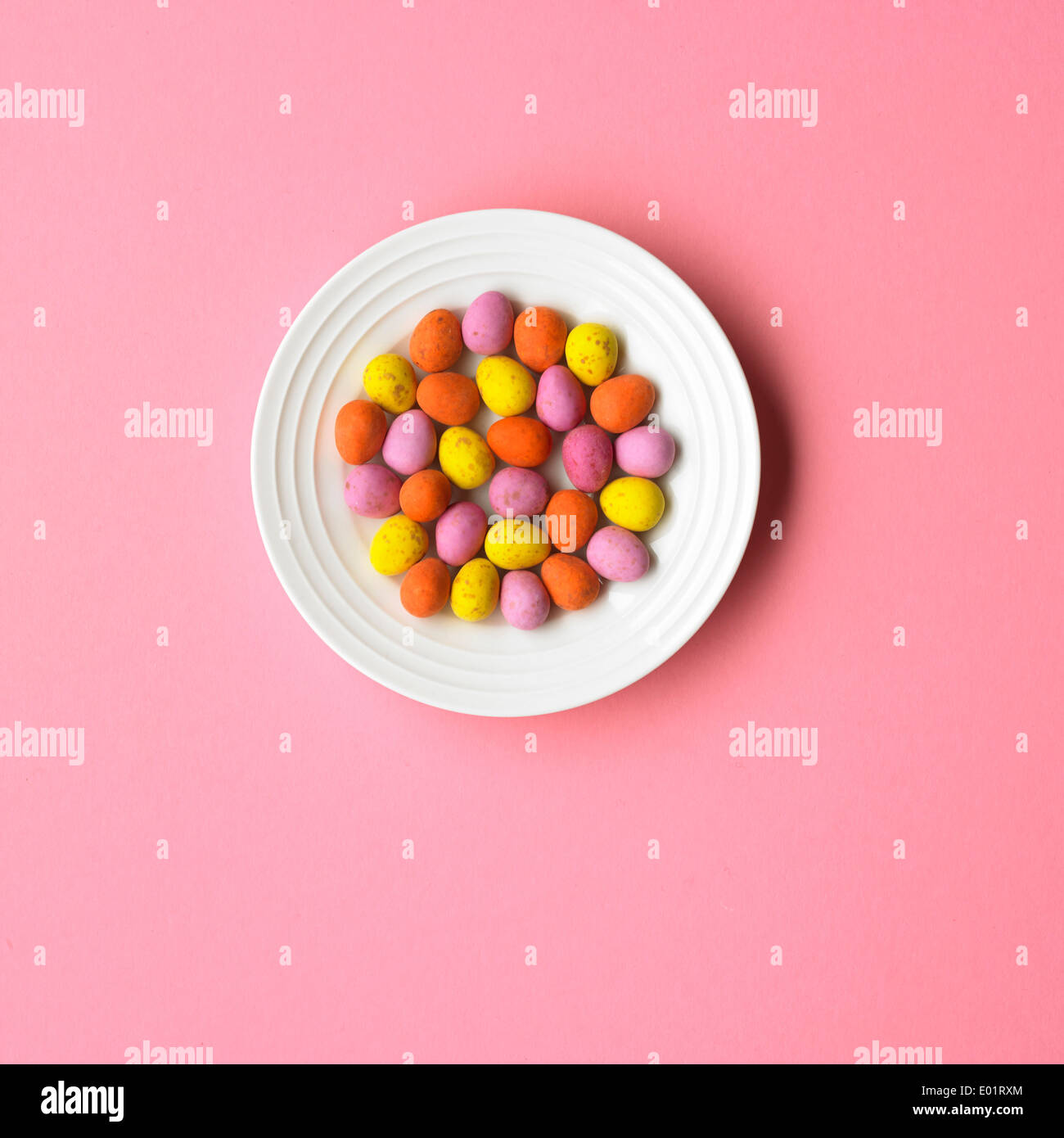 Pale pink background with white plate and multi-coloured mini eggs ...