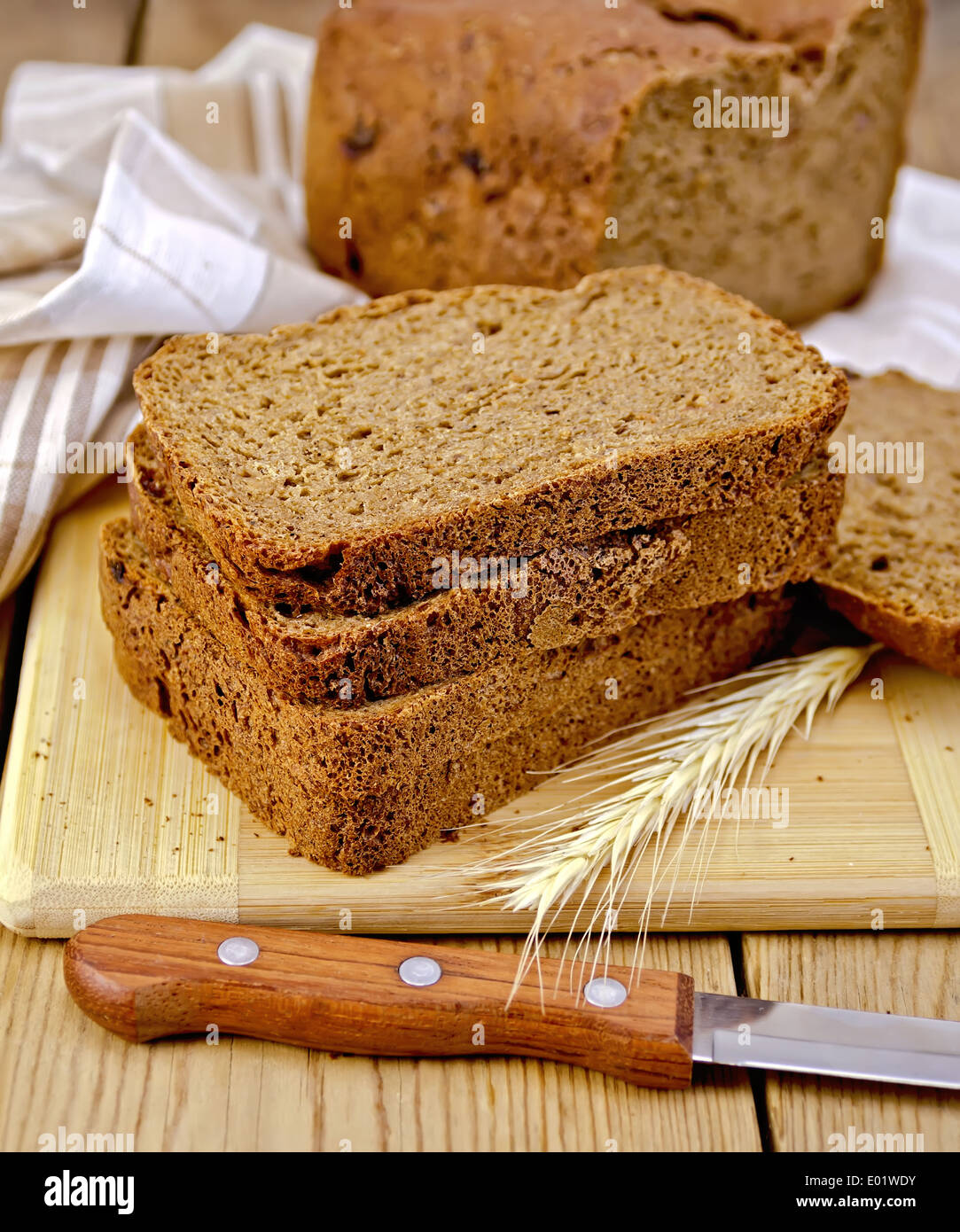 A stack of slices of rye homemade bread with a knife and rye spikelet ...